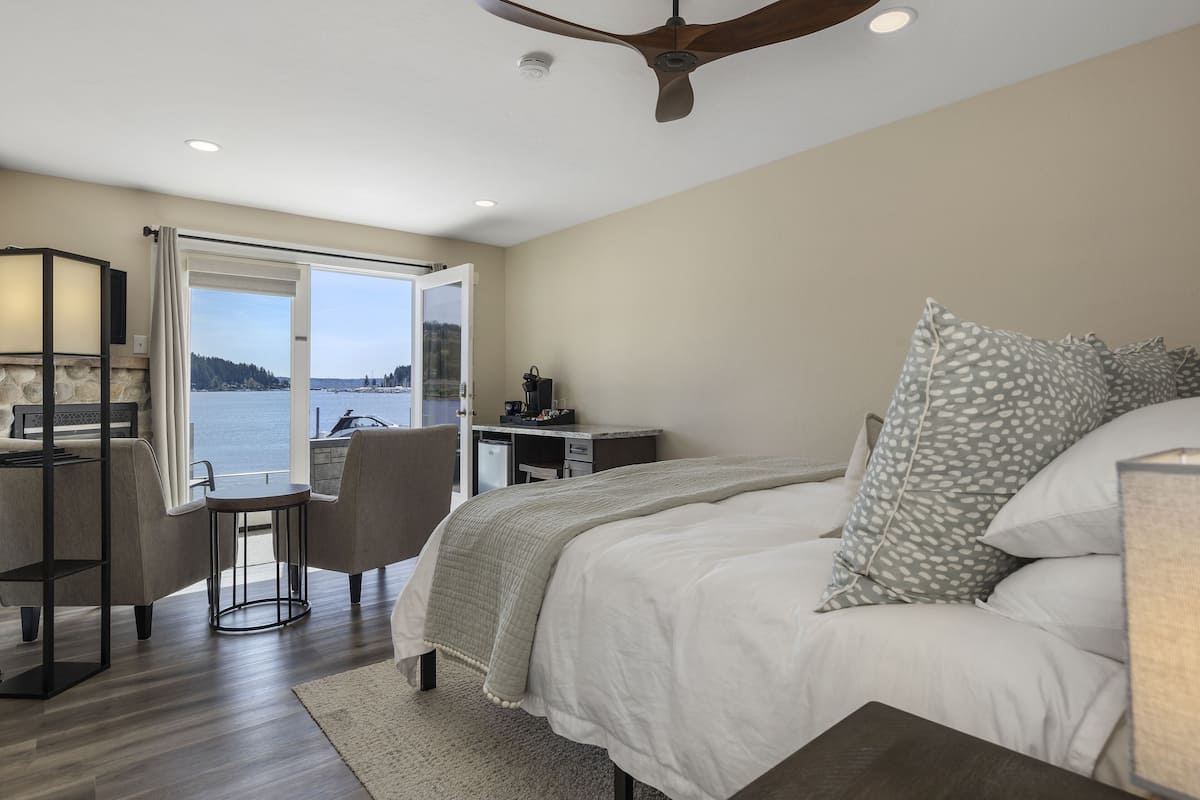 Quarto com cama, escrivaninha e cadeira. Janela com vista para a água.