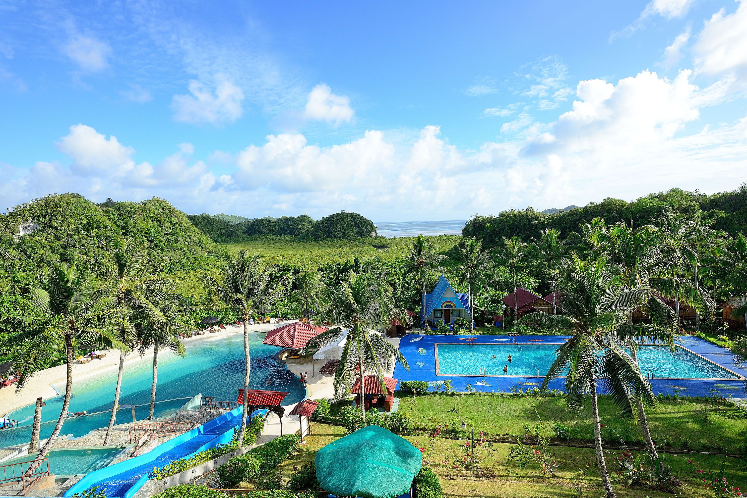 Um resort com piscina, praia e vegetação exuberante.