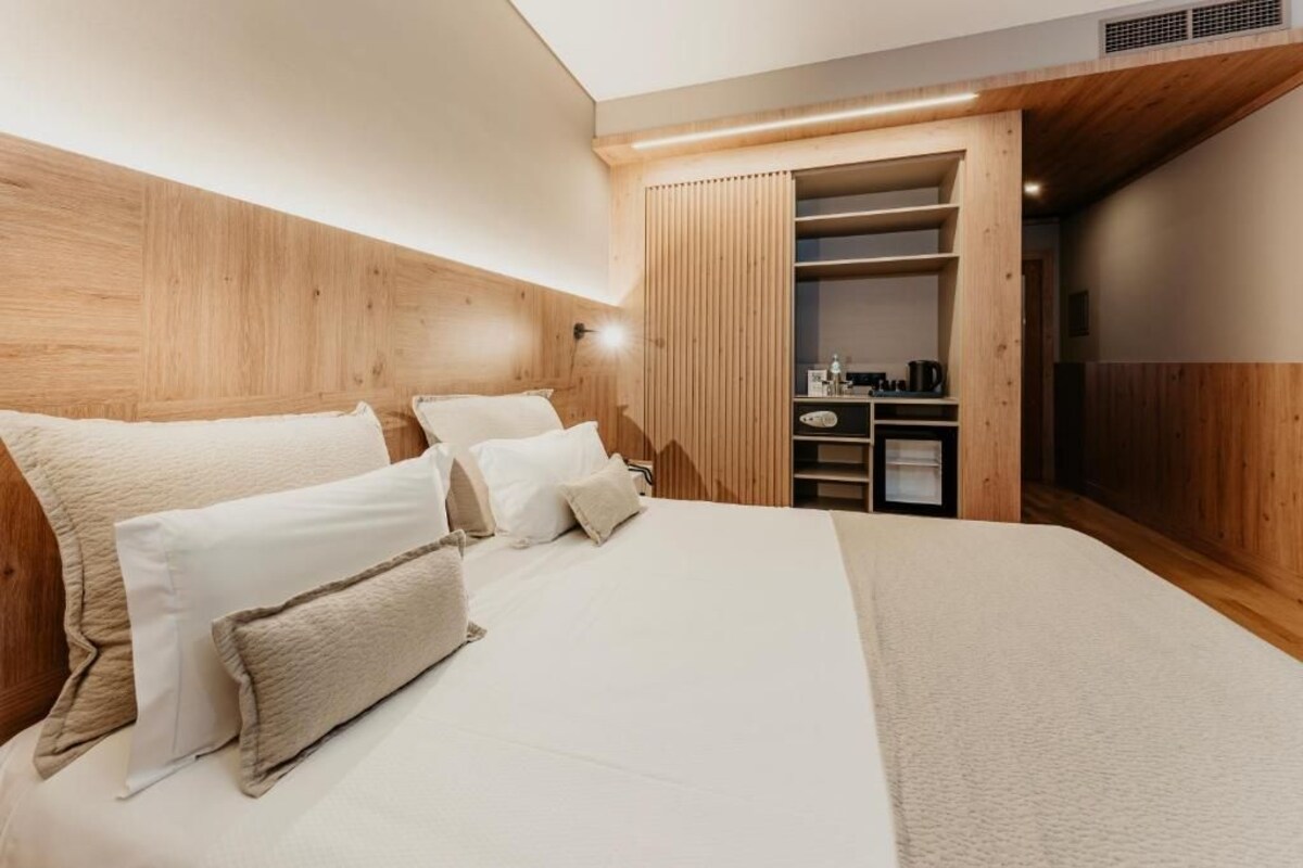 Quarto com cama grande, cabeceira de madeira, prateleiras embutidas e mesa de cabeceira.