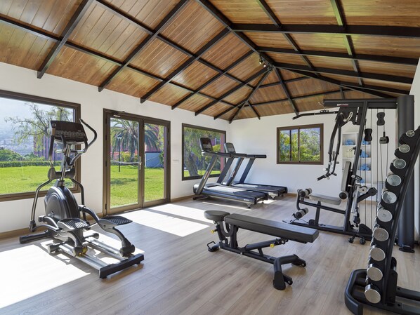 Uma academia ampla com equipamentos de cardio, máquinas de peso e esteira.