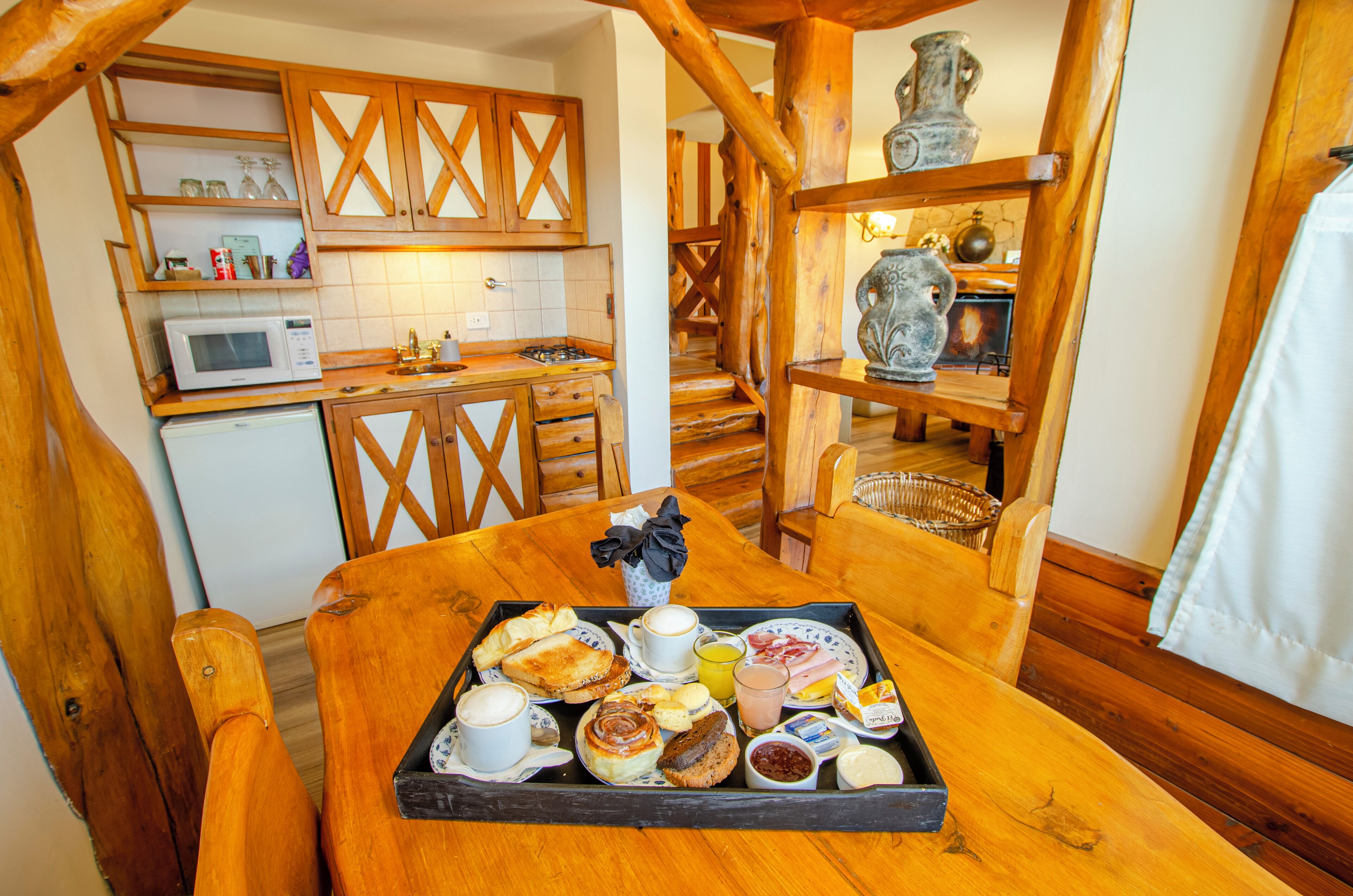 Uma mesa de jantar de madeira com uma bandeja de itens de café da manhã, incluindo doces, café e suco.