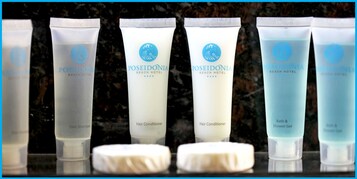 Quatro produtos de cabelo do Hotel Poseidonia Beach: dois shampoos para cabelo, um condicionador e um gel de banho e chuveiro.