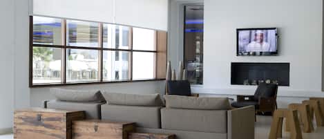 Uma sala de estar moderna com sofá, armários de madeira, televisão e lareira.