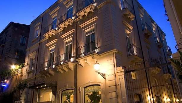 Um edifício de vários andares com estilo arquitetônico clássico, com varandas e grandes janelas.