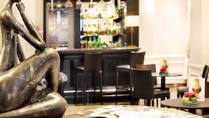 Espaço de bar com uma estátua, balcão e assentos.