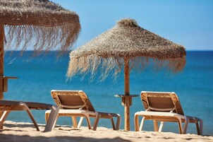 Na praia, areia branca, barracas de praia (sobretaxa), espreguiçadeiras 