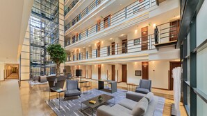 Um hall espaçoso com pé-direito alto, vários andares e um átrio central com uma grande árvore.