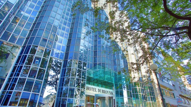 Um hotel moderno com fachada de vidro e uma placa com a inscrição 'HOTEL DUBROVNIK'.