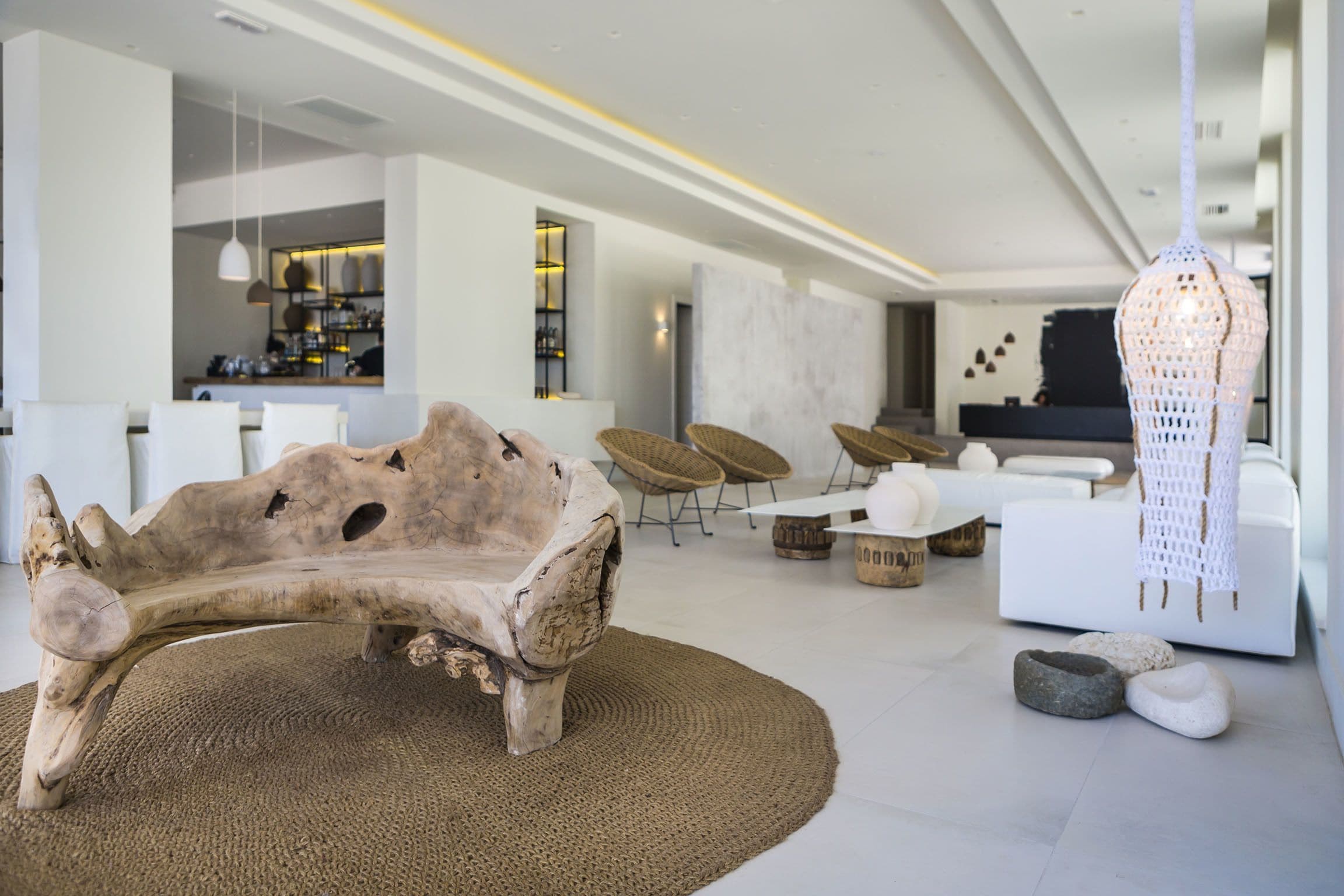 Uma sala de estar moderna com uma mesa de centro de madeira única, assentos confortáveis e um elegante candeeiro suspenso.