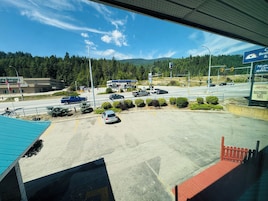 Um estacionamento com vários carros e um posto de combustível ao fundo.