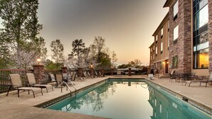 Uma área de piscina com espreguiçadeiras e um edifício com fachada de pedra.