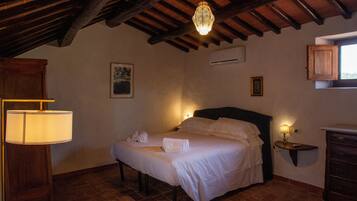Um quarto com cama, mesa de cabeceira, luminária, cômoda e janela.