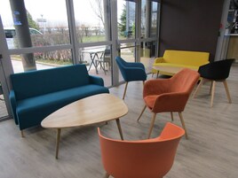 Uma área de estar interna moderna com um sofá azul, cadeiras laranja e um sofá amarelo.