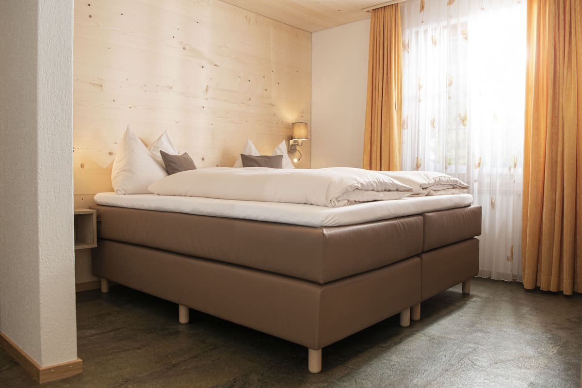 Uma cama grande com cabeceira de madeira, mesa de cabeceira e uma luminária.