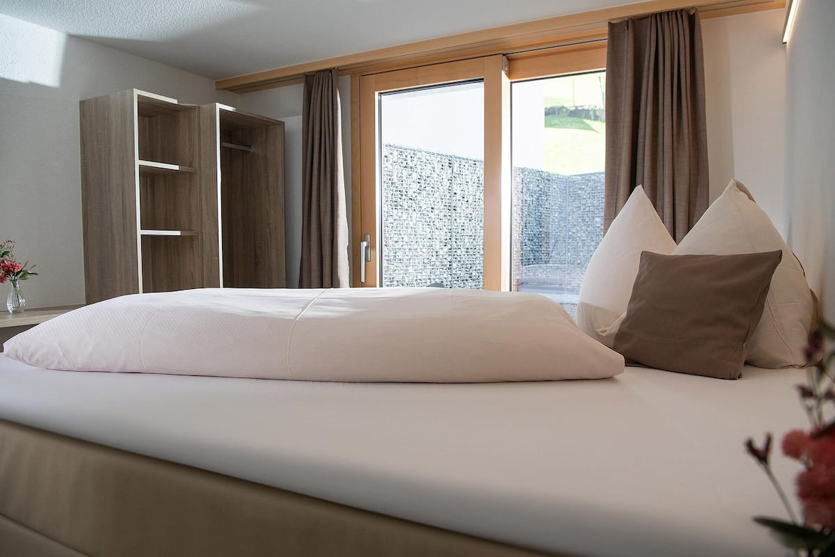 Quarto de hotel com uma cama grande, um guarda-roupa e uma janela com cortinas.