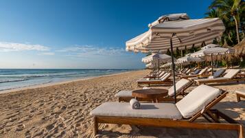 Praia particular, areia branca, espreguiçadeiras, guarda-sóis