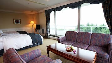 Quarto de hotel com cama, sofá, mesa de centro e televisão.