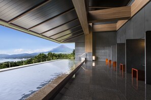 Área interna de piscina moderna com vista para uma montanha e um corpo de água.