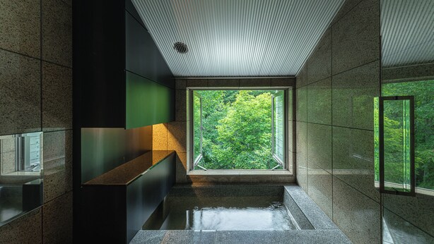 Casa de banho moderna com banheira integrada, uma grande janela com vista para o verde e um design elegante.