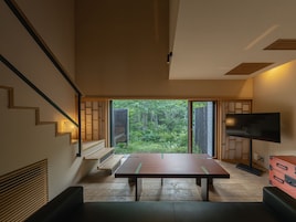 Interior moderno com escada de madeira, uma mesa grande e uma TV.
