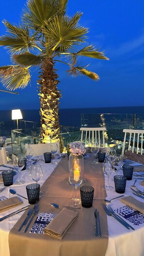 Disposição para refeições ao ar livre, com uma mesa posta, com vista para o horizonte urbano ao entardecer.