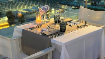 Mesa posta para dois com vista para a paisagem urbana ao entardecer.