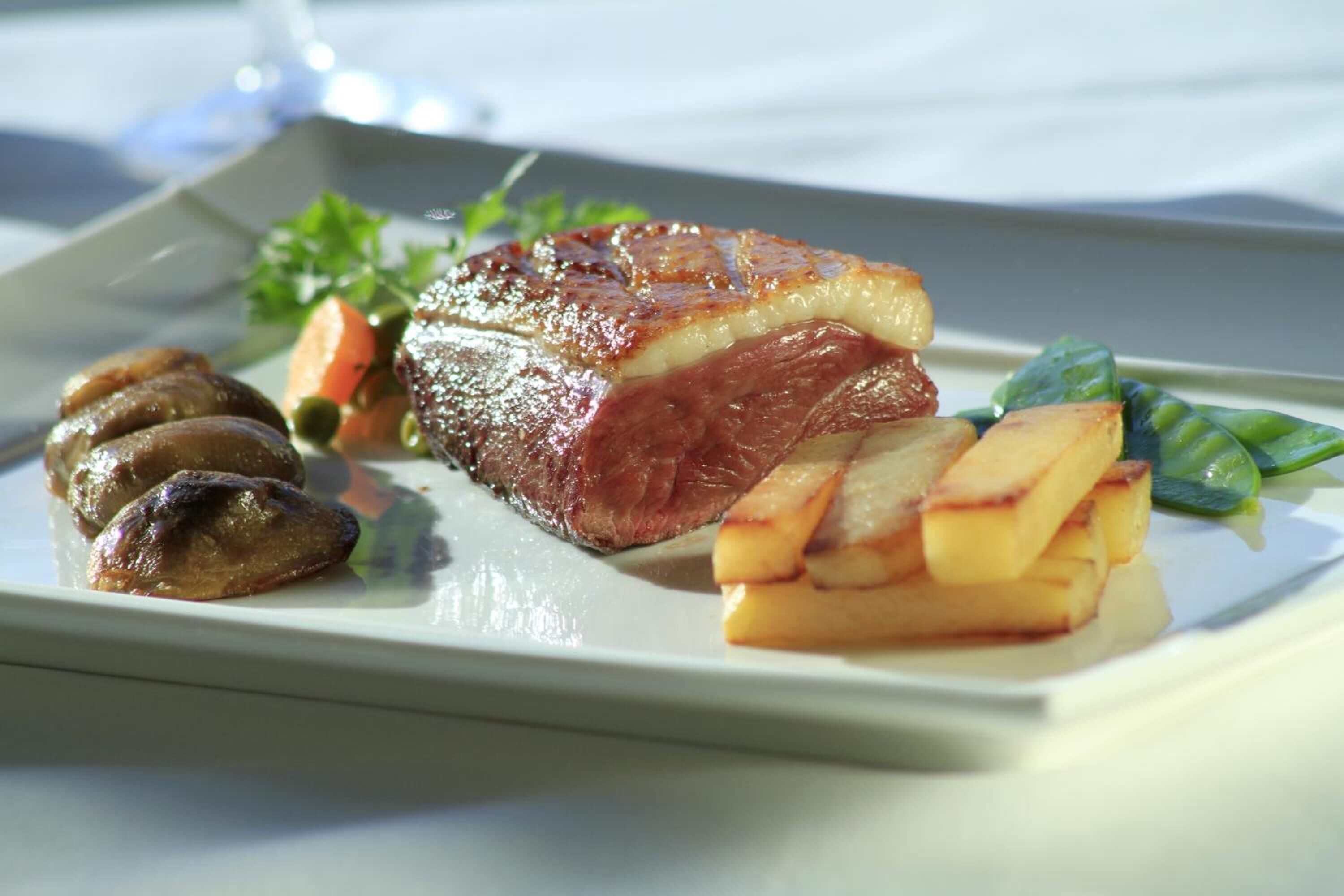 Um prato com carne, cogumelos e batatas assadas.