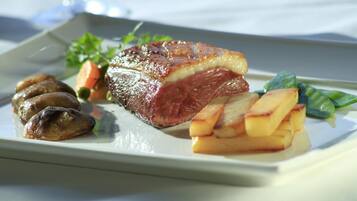 Um prato com carne, cogumelos e batatas assadas.