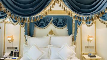 Um quarto luxuoso com uma cama grande, cortinas douradas e azuis ricamente decoradas e arandelas combinando.