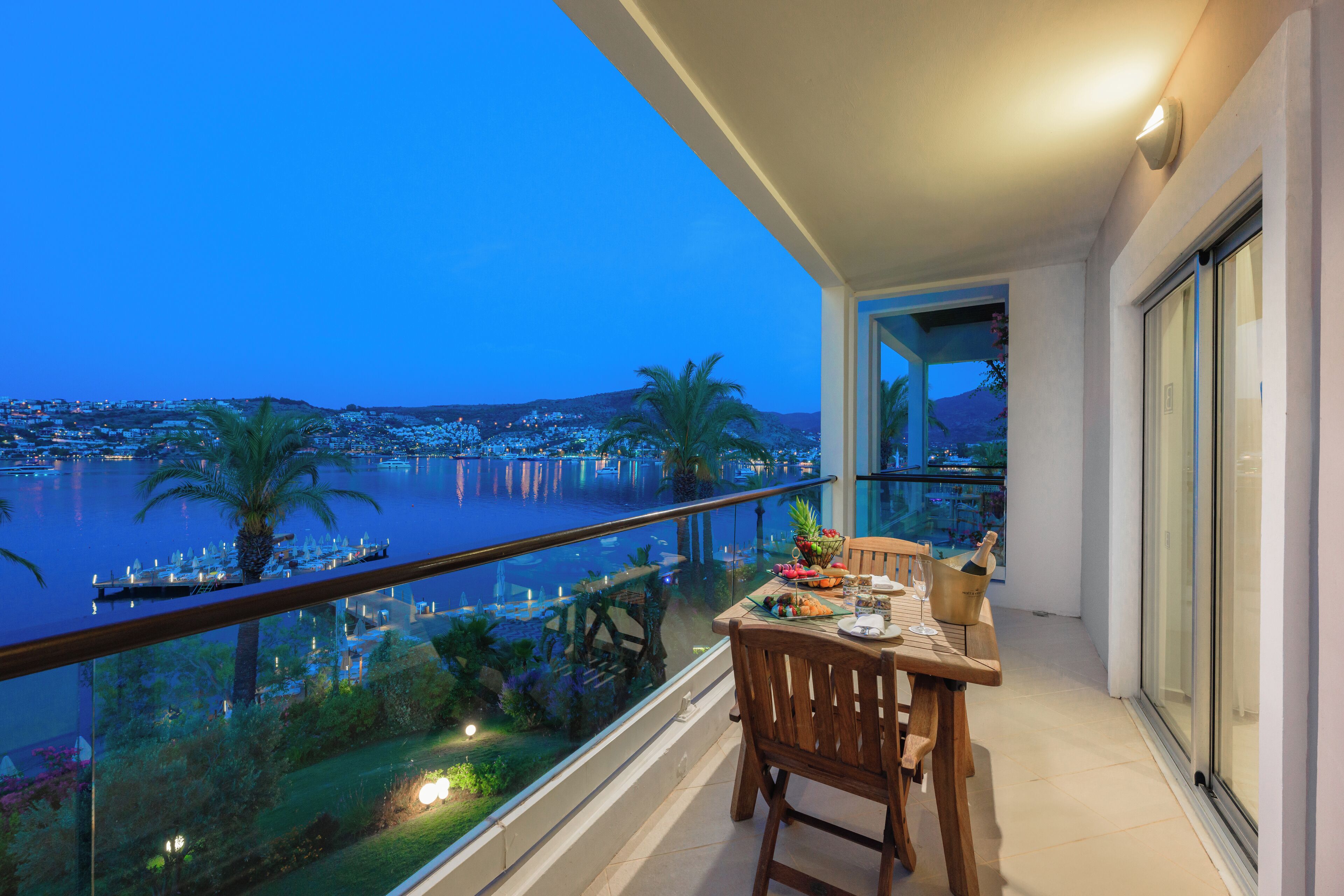 Varanda com mesa posta para refeições, com vista para um porto e um corpo de água.