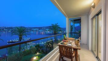 Varanda com mesa posta para refeições, com vista para um porto e um corpo de água.