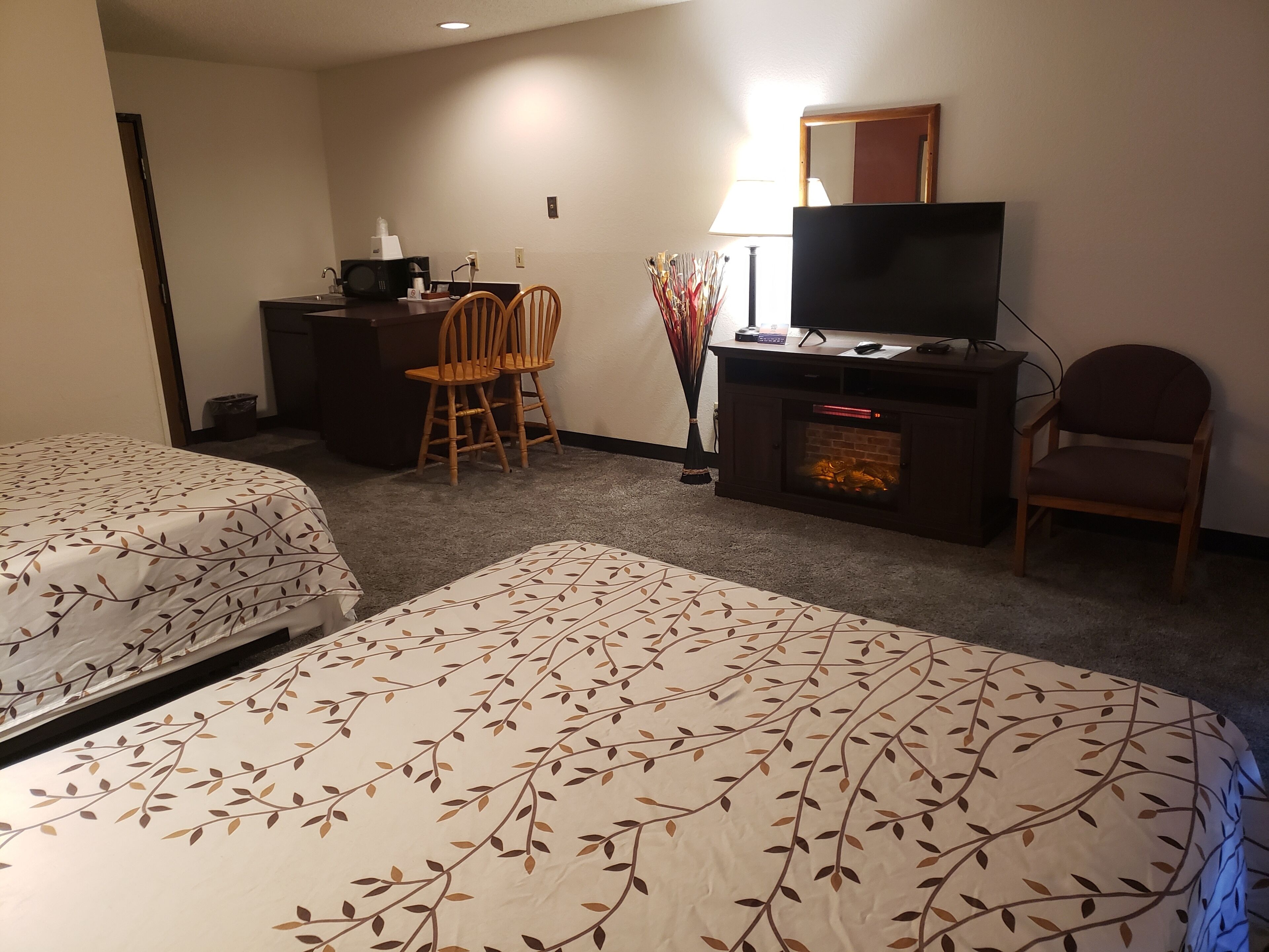 Quarto de hotel com duas camas, uma escrivaninha com computador, televisão e lareira.