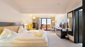 Quarto de hotel com uma cama grande, uma escrivaninha, uma cadeira e uma televisão.
