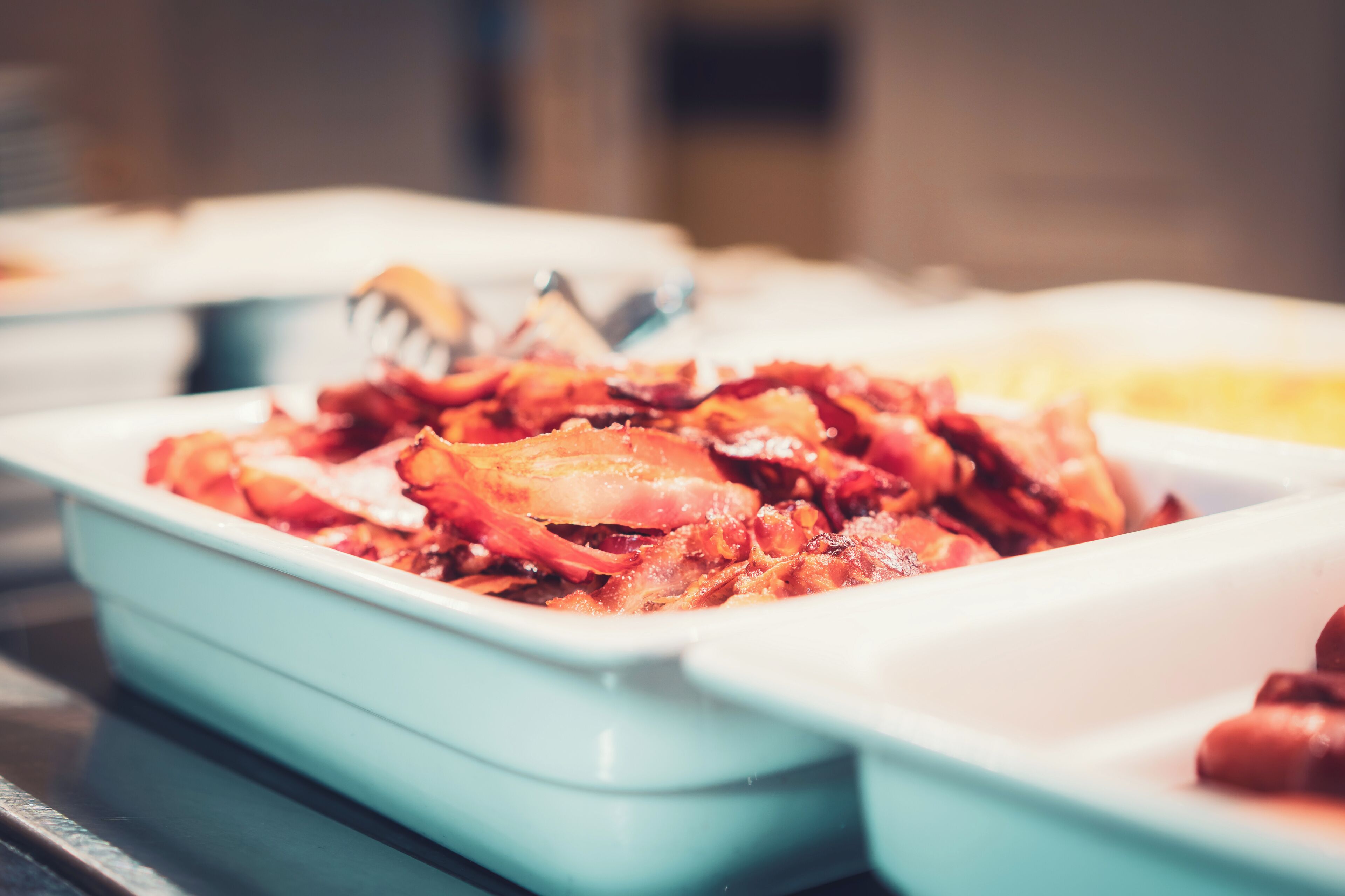 Buffet com diversos pratos, incluindo um recipiente grande com carne fatiada.