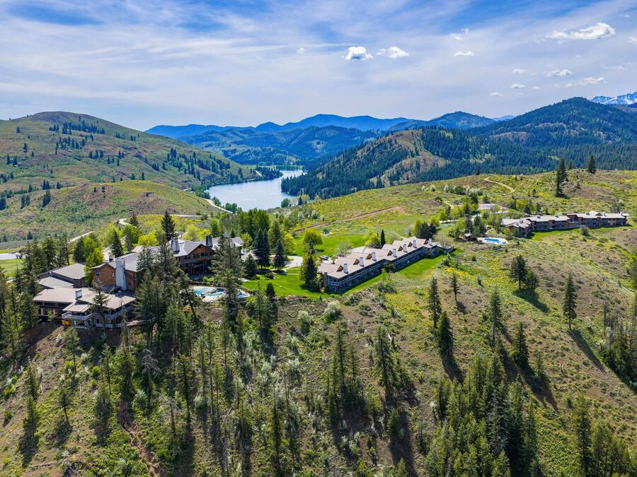 Resort com vários edifícios, piscina e um lago rodeado por montanhas.