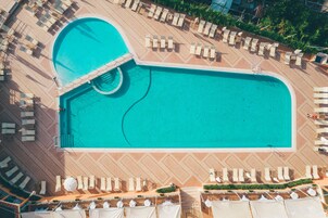 Vista aérea de uma piscina cercada por espreguiçadeiras e guarda-sóis.