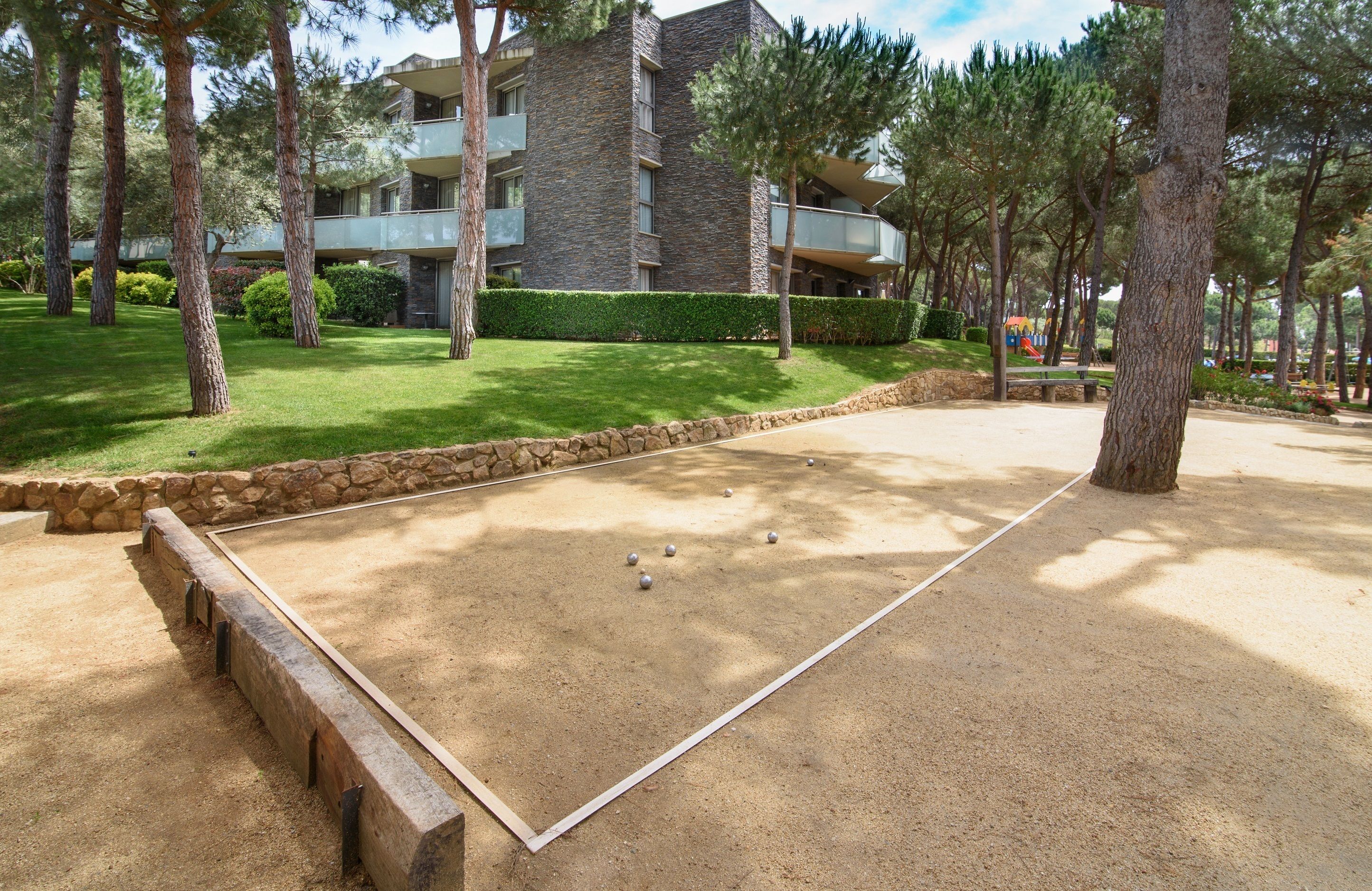 Um pátio com campo de croquet, cercado por árvores e um edifício de pedra.