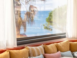Quarto com vista para o mar através de uma janela.