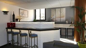 Uma cozinha moderna com área de bar, banquetas e um vaso de planta.