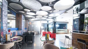 Um interior moderno com luminárias redondas no teto, um balcão de recepção e áreas de estar.