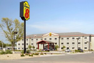 Um hotel Super 8 com entrada sob uma cobertura vermelha, diversas janelas e um estacionamento com vários carros.