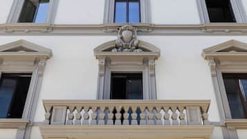Um edifício com arquitetura clássica, apresentando uma varanda central com balaustradas ornamentadas e colunas decorativas.