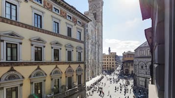 Uma praça histórica com arquitetura clássica, incluindo fachadas ornamentadas e uma torre imponente.