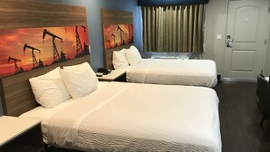 Quarto de hotel com duas camas, mesa de cabeceira, escrivaninha e um quadro com bombas de óleo.