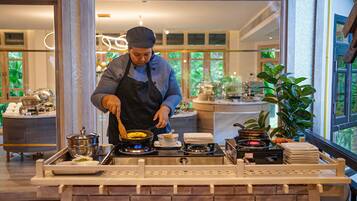 Um chefe de cozinha prepara alimentos em um buffet, com diversos pratos e utensílios de cozinha.