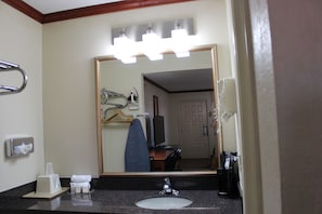 Uma casa de banho de hotel com um espelho grande, uma pia e um porta-toalhas.