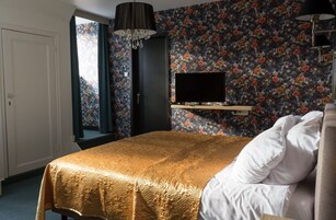 Quarto com cama, televisão na parede e papel de parede floral.