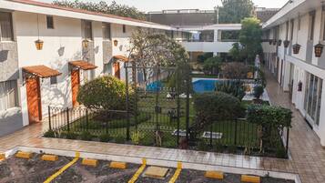 Um pátio com piscina, rodeado por edifícios com varandas e lanternas penduradas.