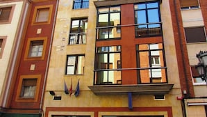 Um edifício com vários andares, entrada central, janelas amplas e varandas.