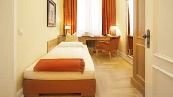 Quarto de hotel com cama, escrivaninha, cadeira e porta.